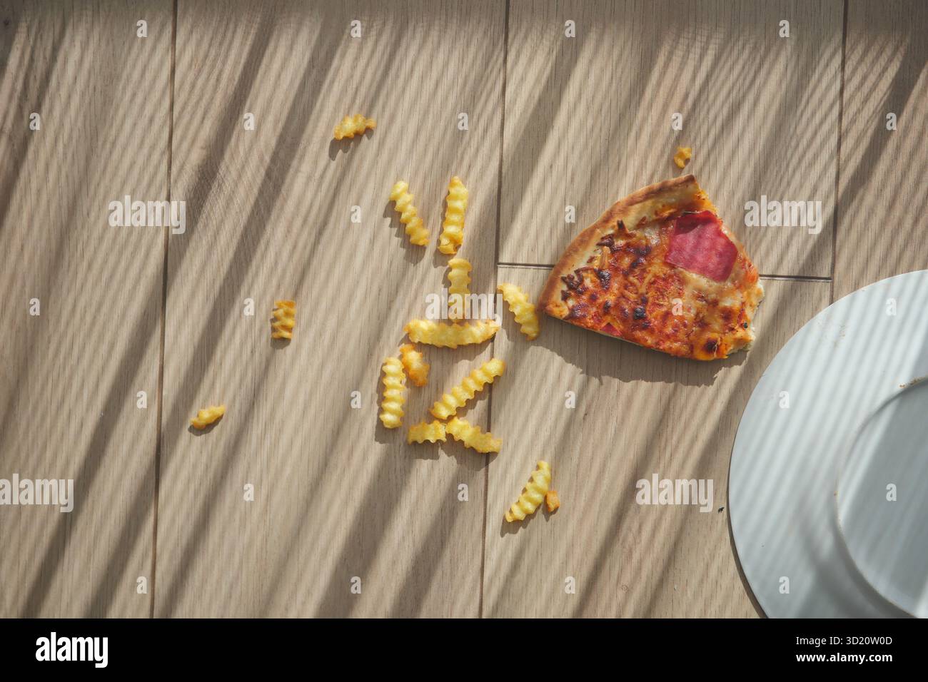 Crusty pizza slice and fries drop on wooden floor Stock Photo - Alamy
