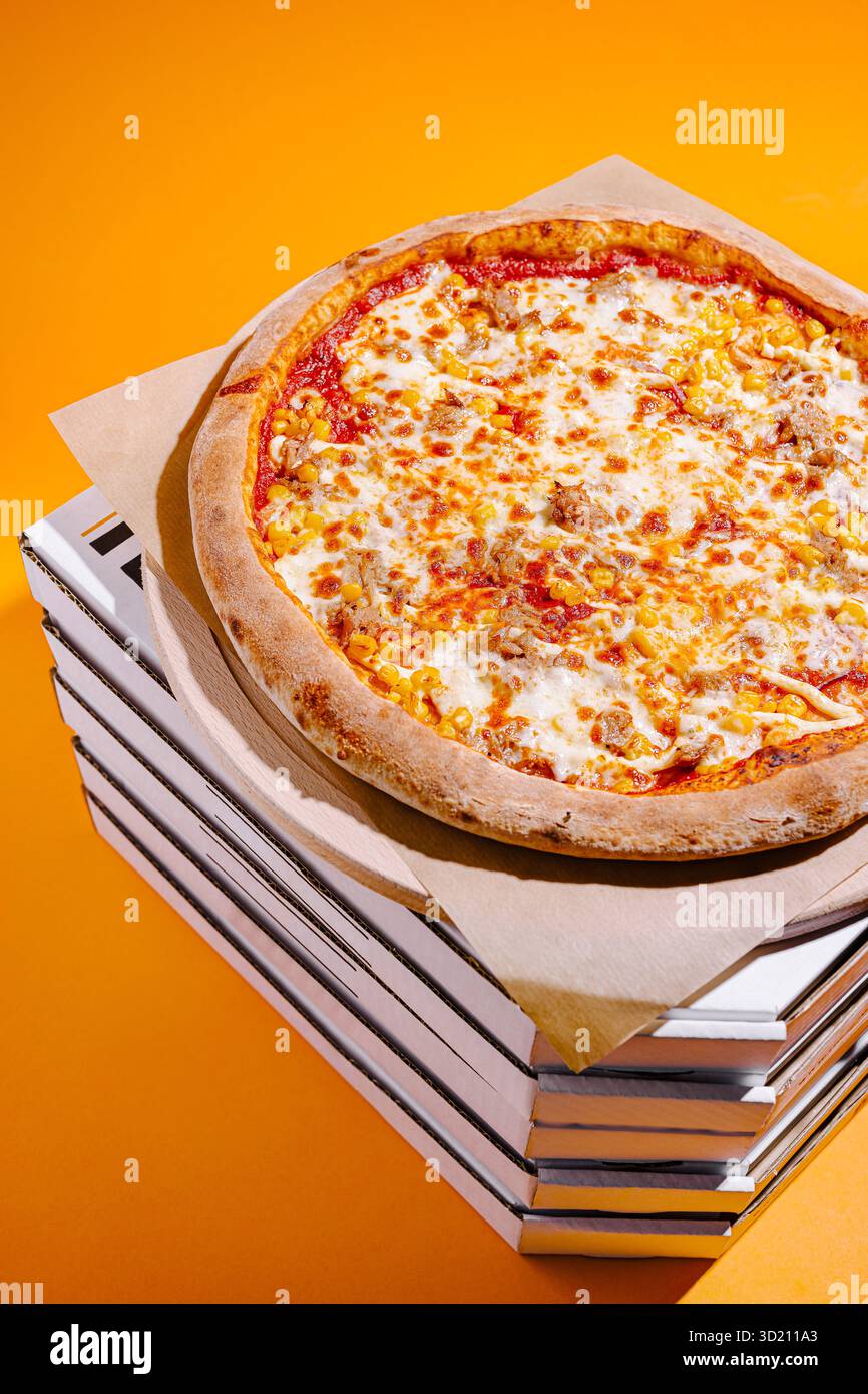 A freshly made pizza sits atop a stack of boxes against a vibrant ...
