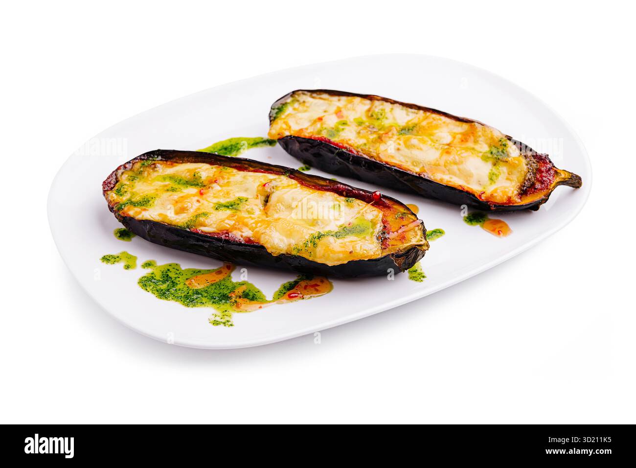 Stuffed eggplants filled with melted cheese sit on a white plate ...
