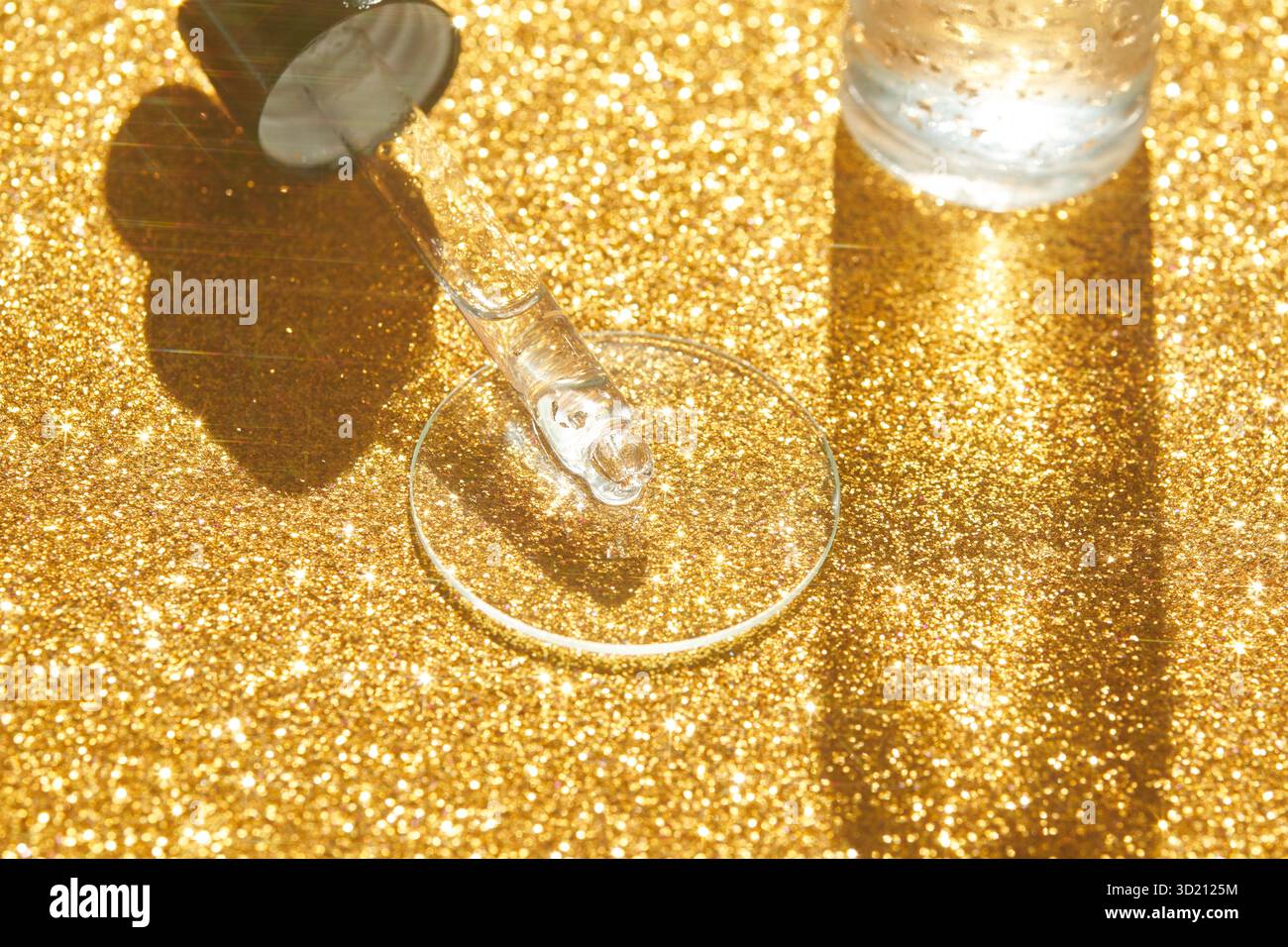Sparkling gold glitter serum dropper on reflective surface with light ...