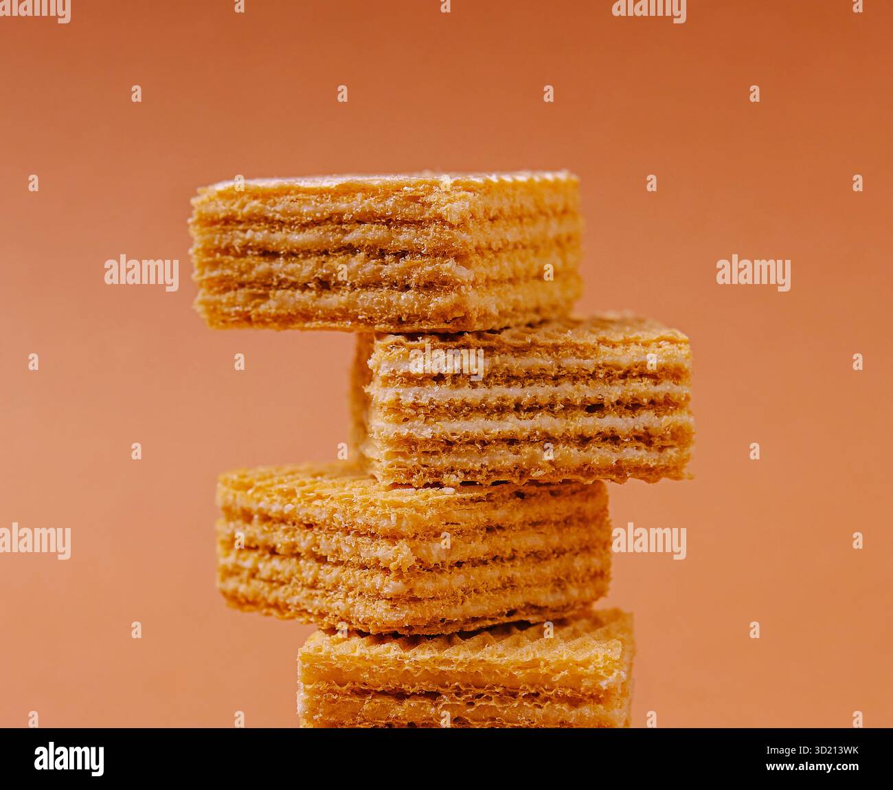 Stack of crispy wafers on a warm orange background creating a visually ...