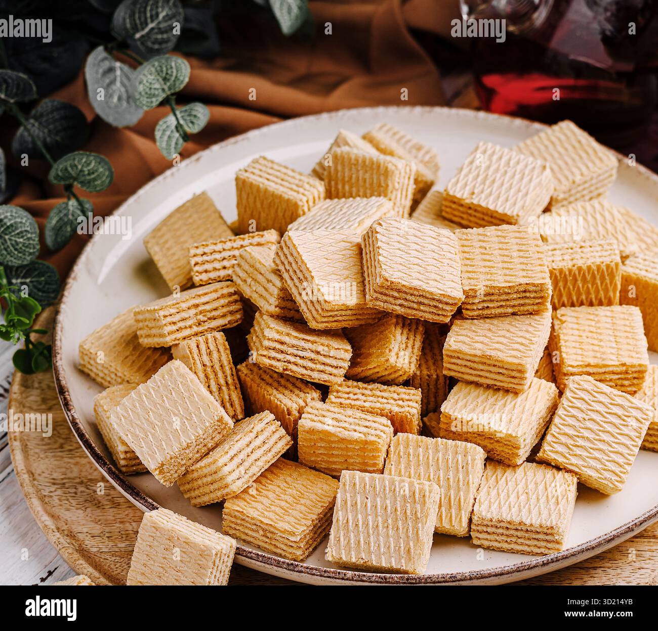 A plate is filled with neatly stacked wafers in a cozy setting. The ...
