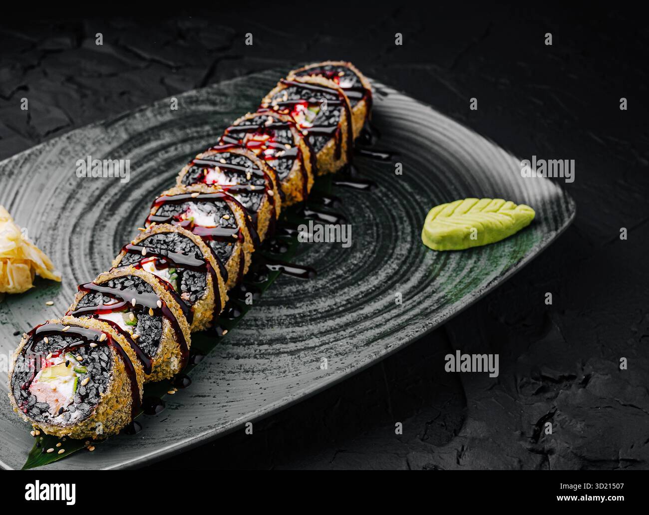 Delicious sushi roll plated beautifully on a dark textured surface with ...