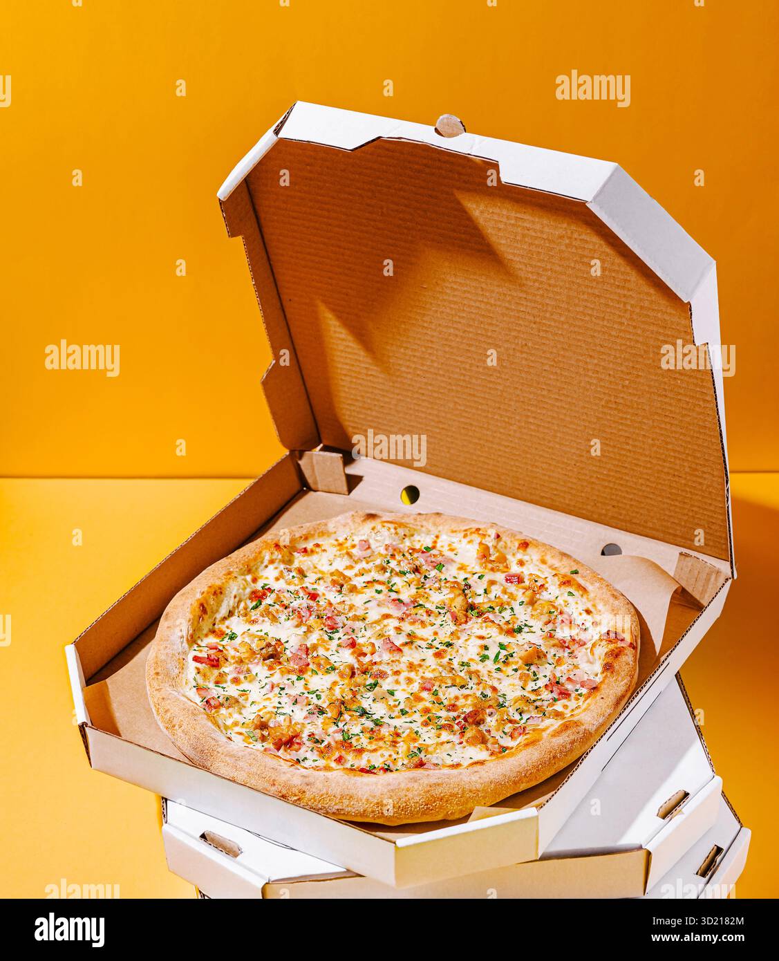 Delicious freshly baked pizza in an open delivery box against a bright ...