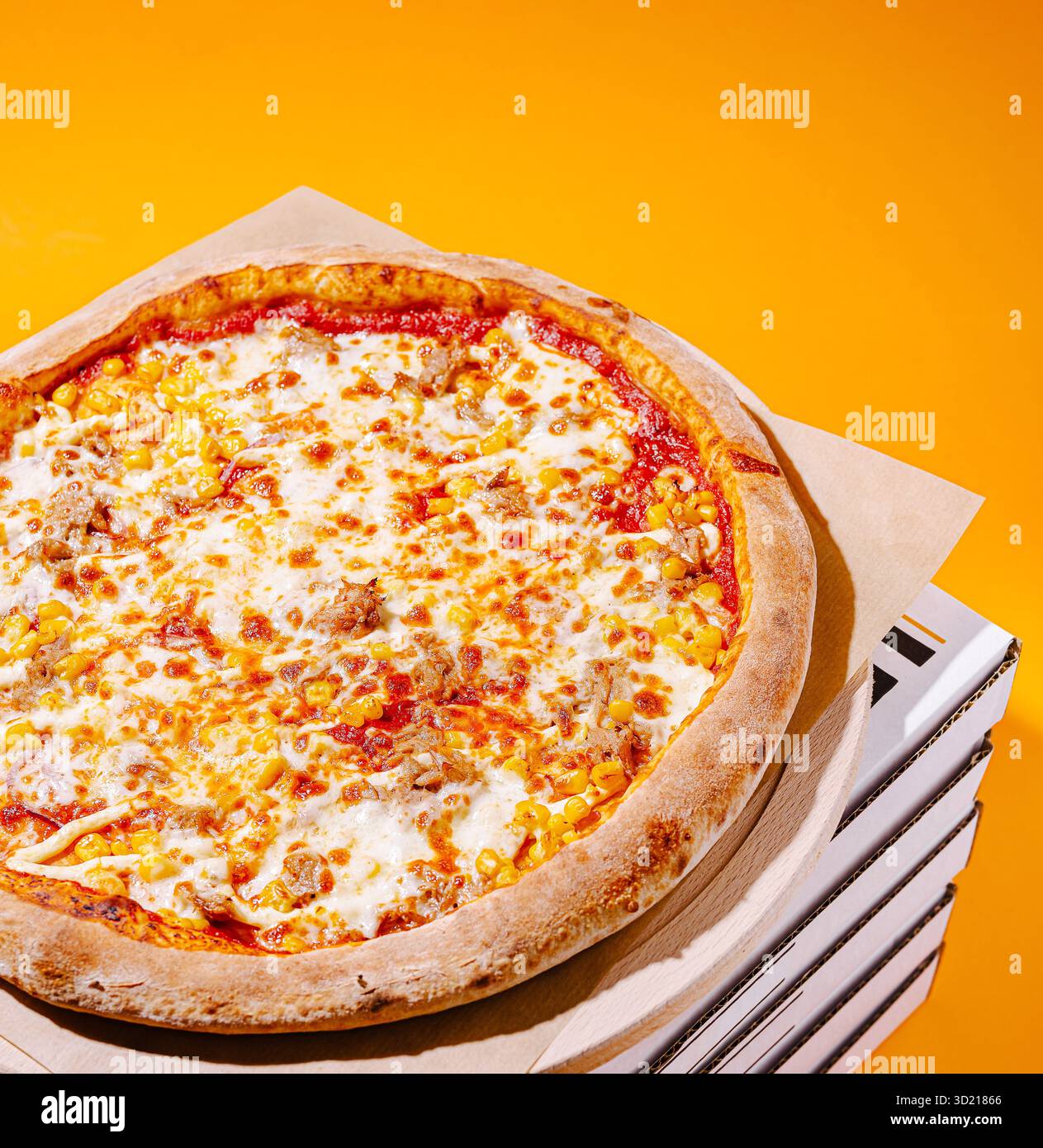 A tantalizing pizza sits on a stack of pizza boxes, showcasing a golden ...