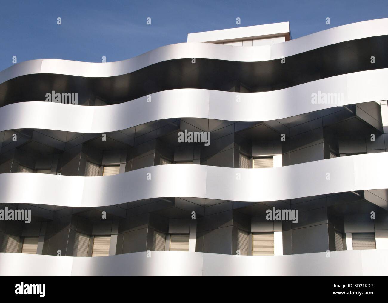 Modern building featuring a wavy facade with balconies and closed ...