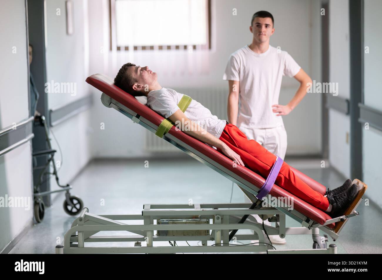 Rehabilitation with Standing Frame.Male therapist assists patient with ...