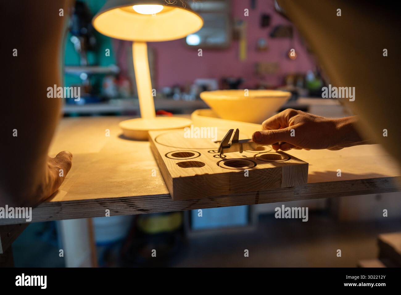 Craftsman using calipers on lamp templates in workshop. Handmade ...