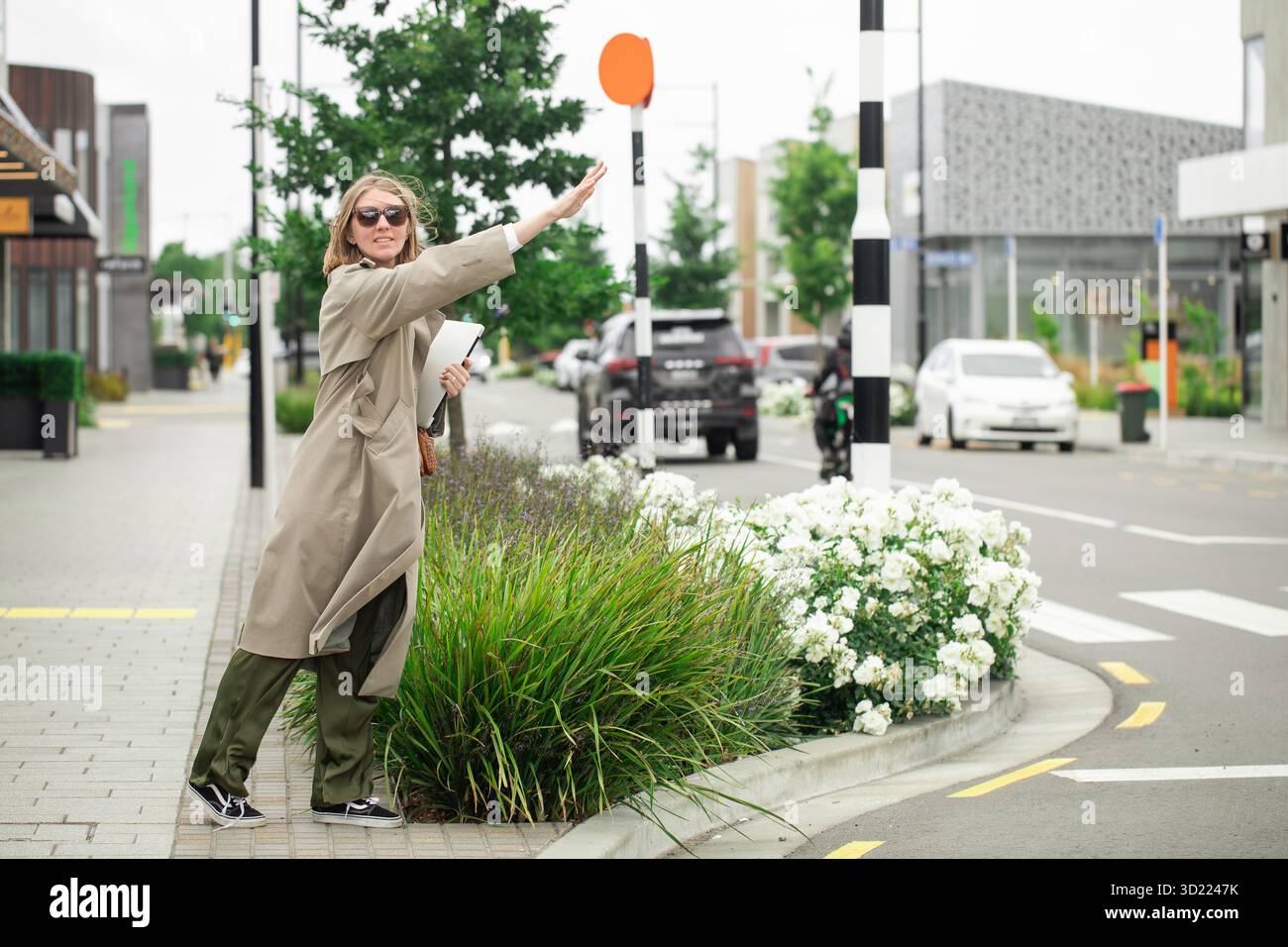 Woman hailing cab on modern city street for urban transportation ...