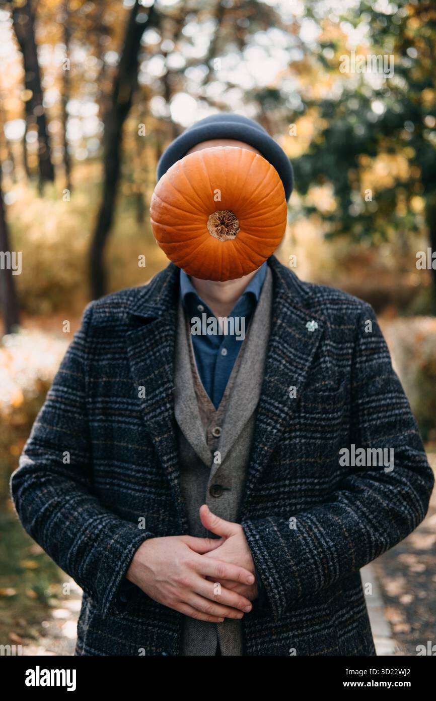 Man standing in a forest path with a pumpkin obscuring his face and ...