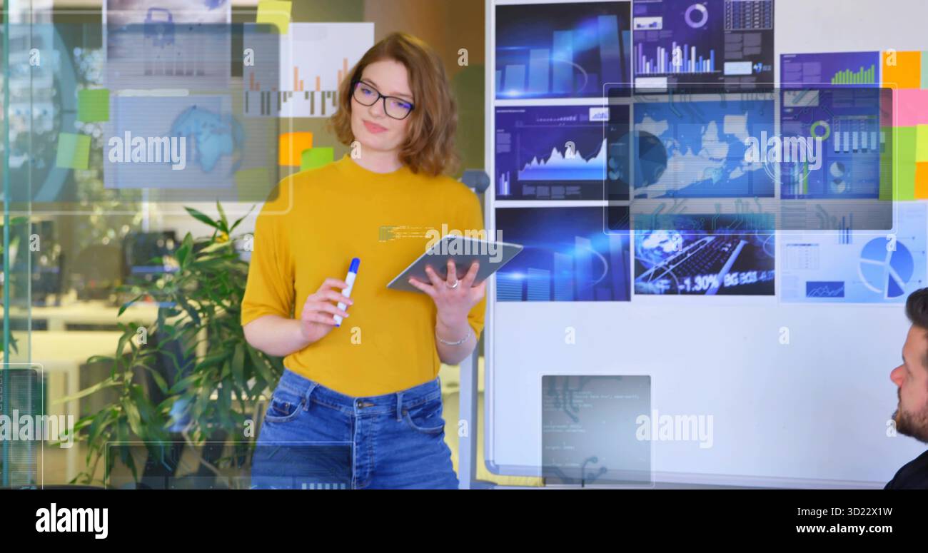 Presenting woman pointing at whiteboard charts in office, with tablet ...
