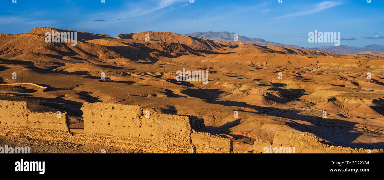 Arid desert landscape with rolling hills and distant mountains under a ...