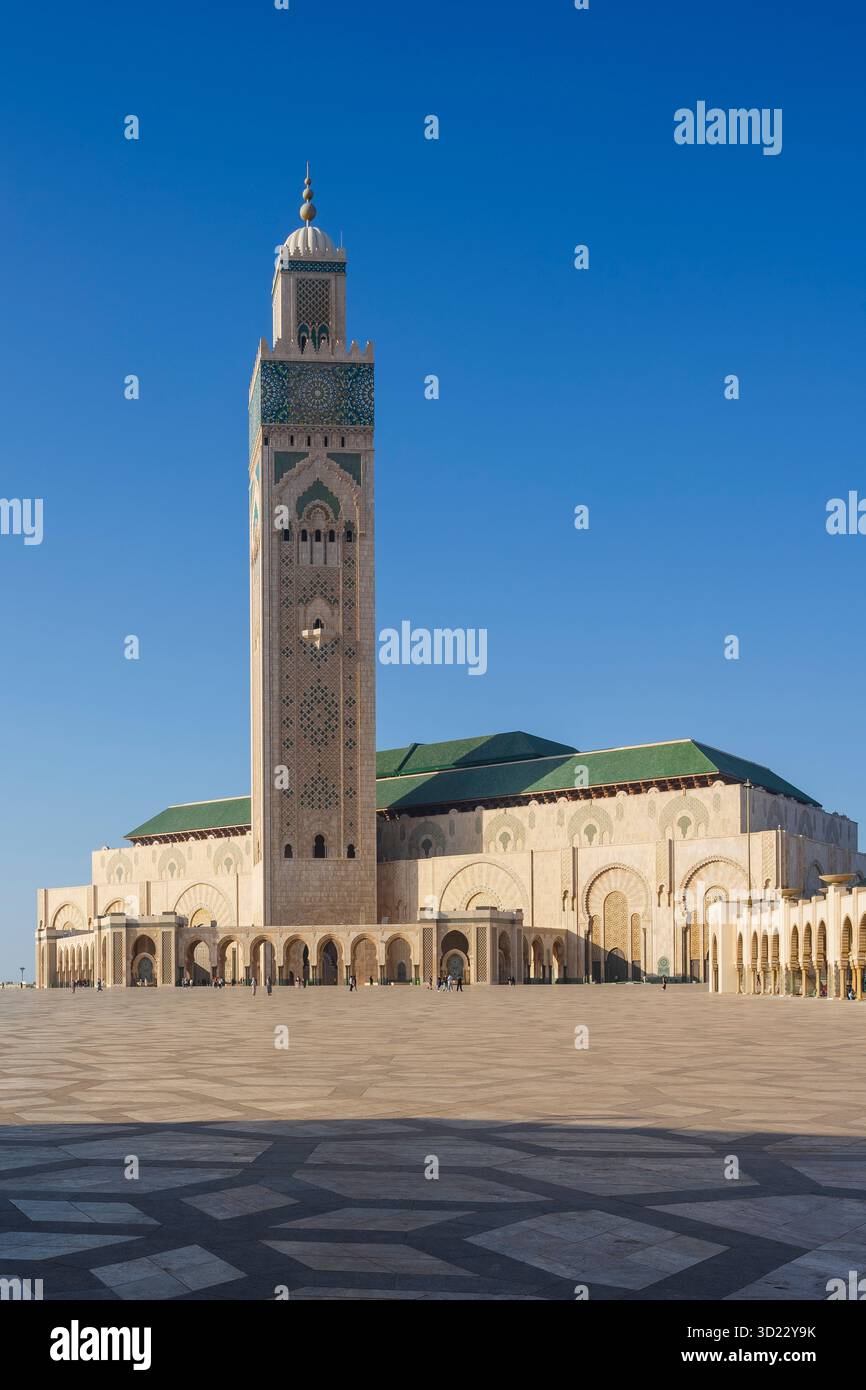 The Hassan II Mosque stands under a clear blue sky with its intricate ...
