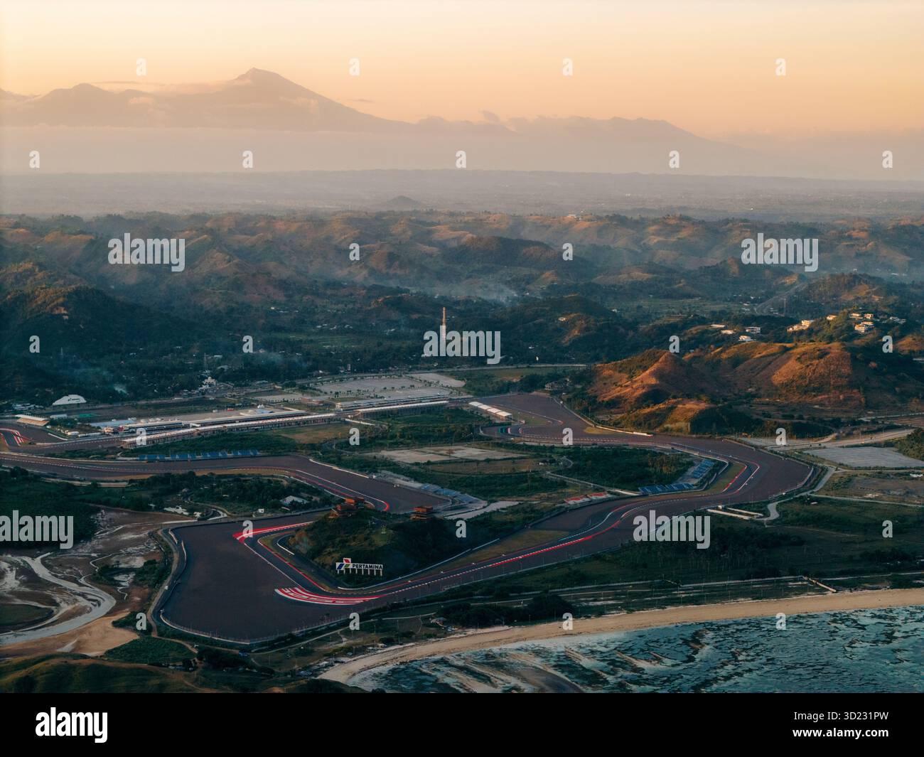 Aerial view of a twisting racetrack during sunset against a mountainous ...