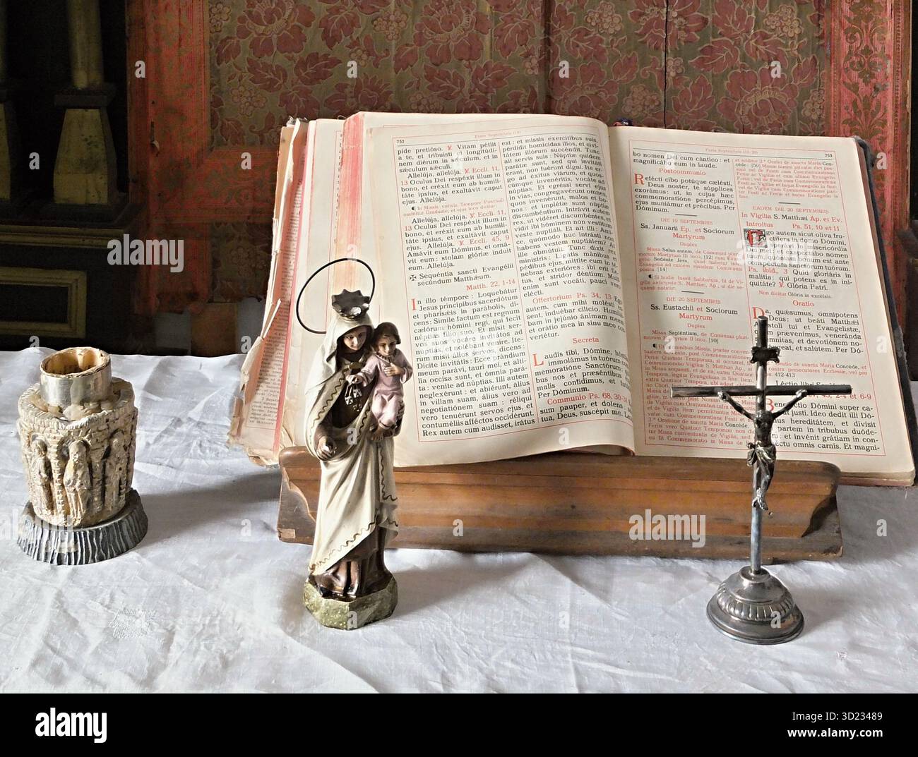 Open bible, crucifix and madonna with child statue resting on altar ...