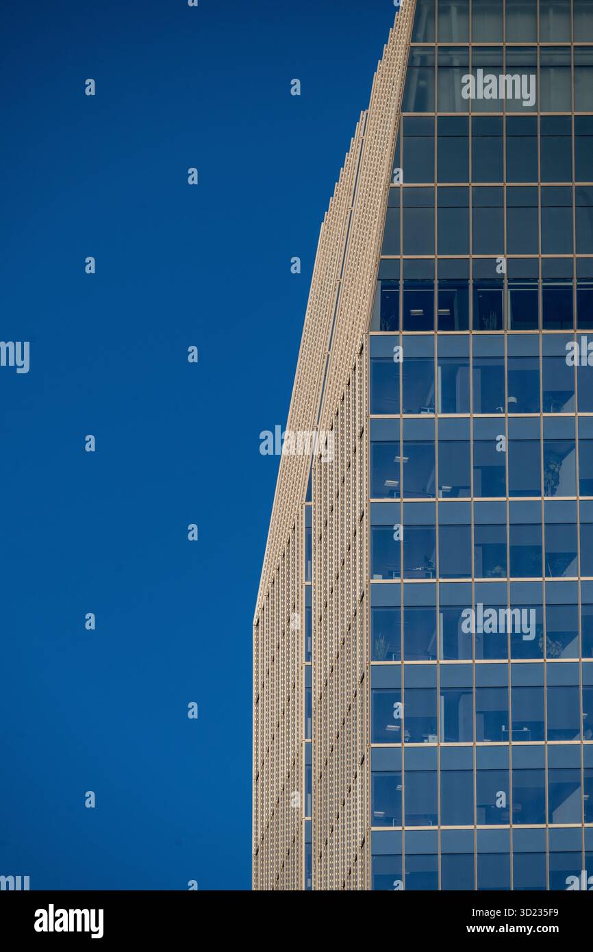 Modern skyscraper facade with glass windows against a clear blue sky ...