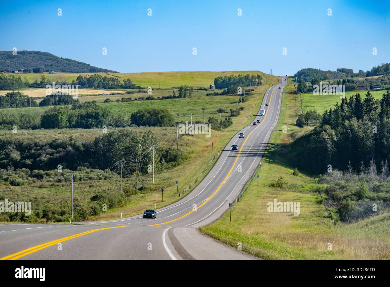 A scenic countryside road stretching into the distance with cars and ...