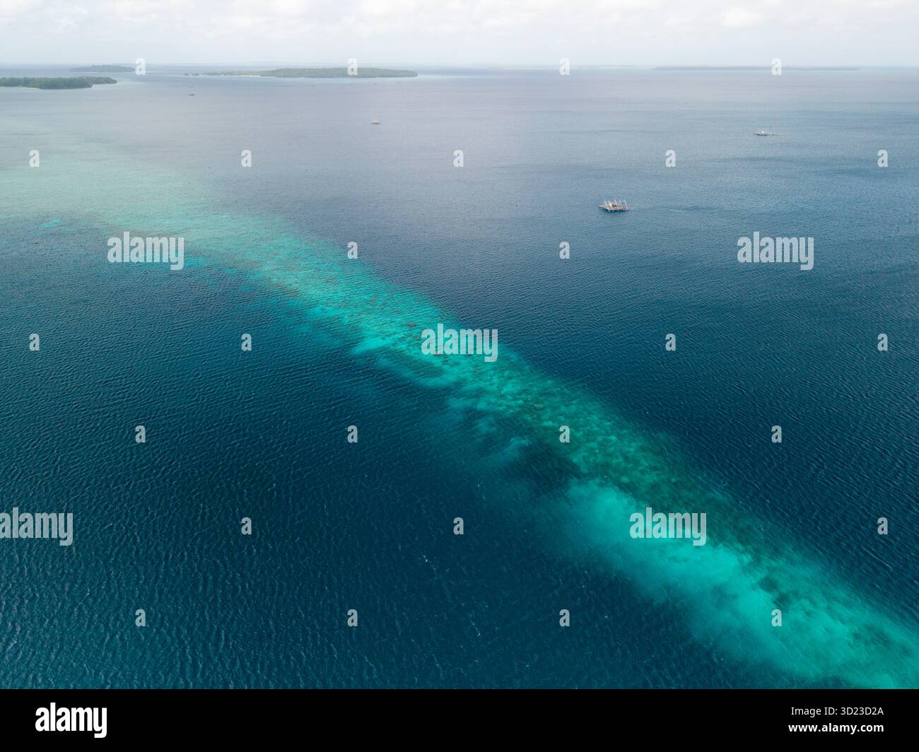 Aerial view of the ocean with a visible coral reef underneath the calm ...