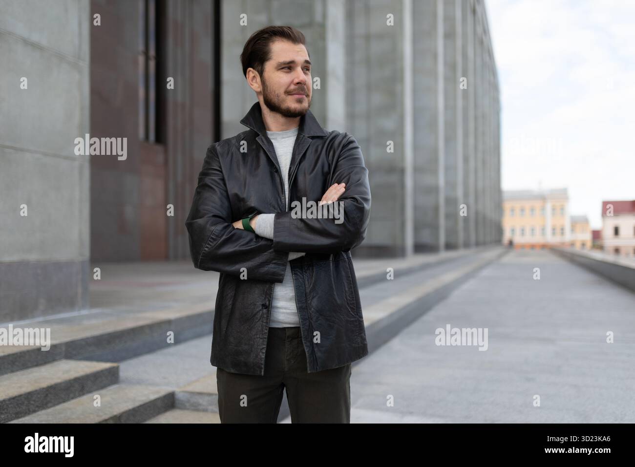 young man with a smile in a pair crossed his arms on his chest outside ...