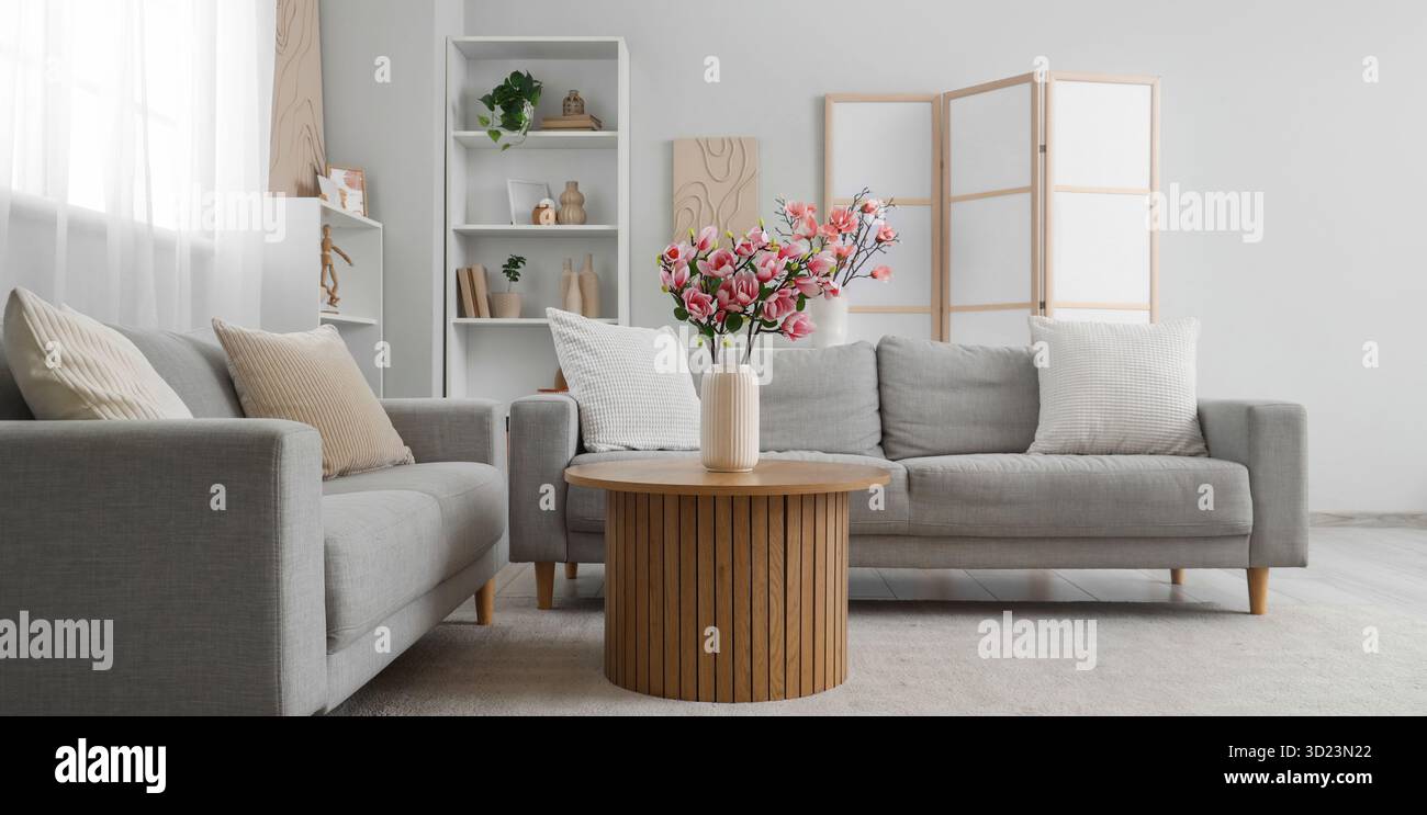 Cozy sofas and magnolia flowers in interior of room Stock Photo - Alamy