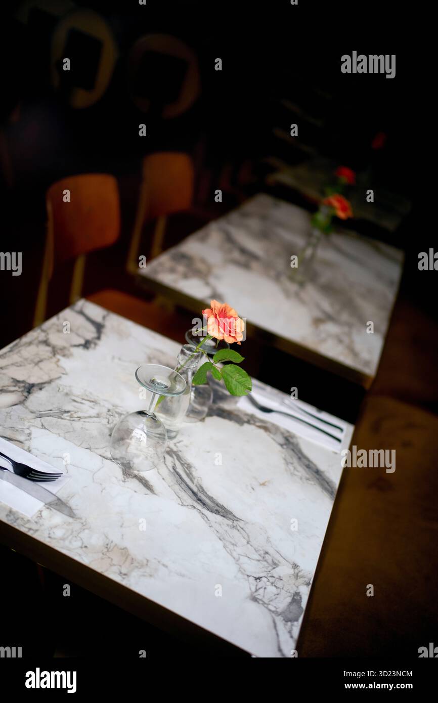Elegant marble tables with roses in a cozy dimly lit restaurant setting ...