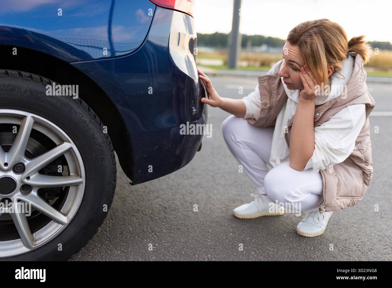 Frustrated female driver sits at the rear bumper of the car and ...