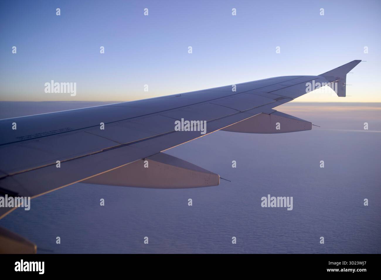 Aircraft wing viewed from a window seat flying above the clouds during ...