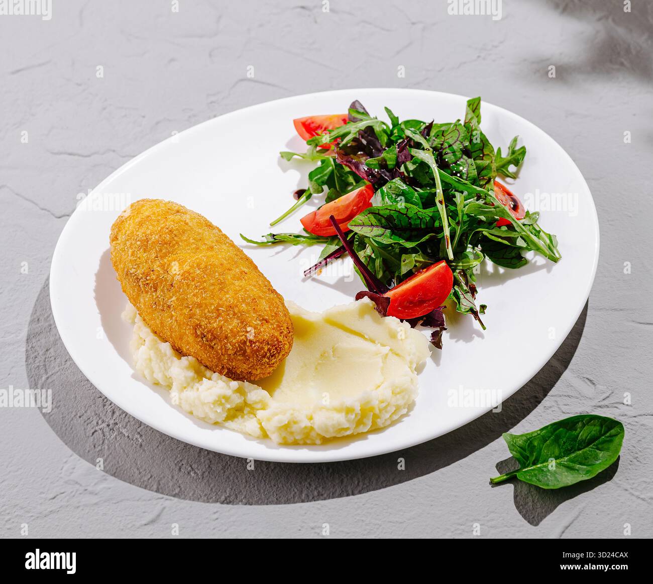 Crispy croquette served with mashed potatoes and fresh salad on a plate ...
