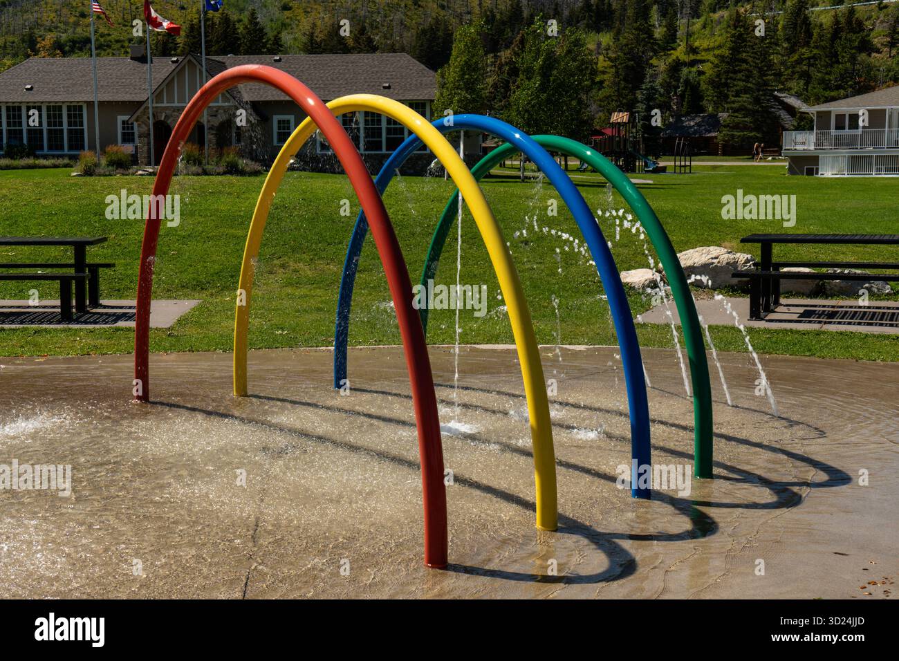 Rainbow water fountain arches in the park for a summer day refreshing ...