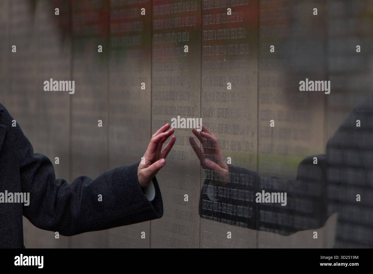 A woman touches the wall with the names of victims during a memorial ...