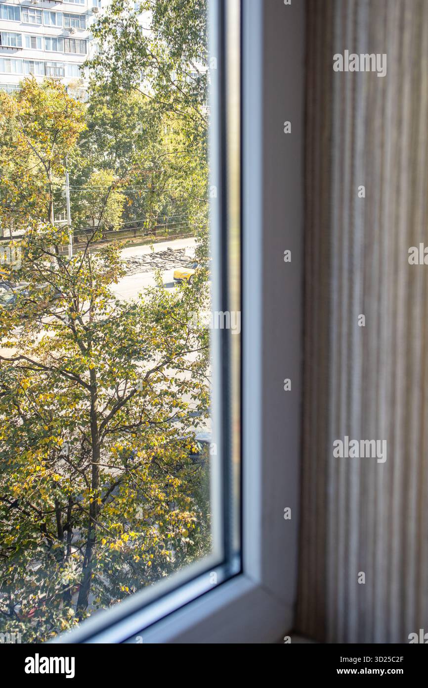 Apartment view through a PVC window to trees and the street with window ...