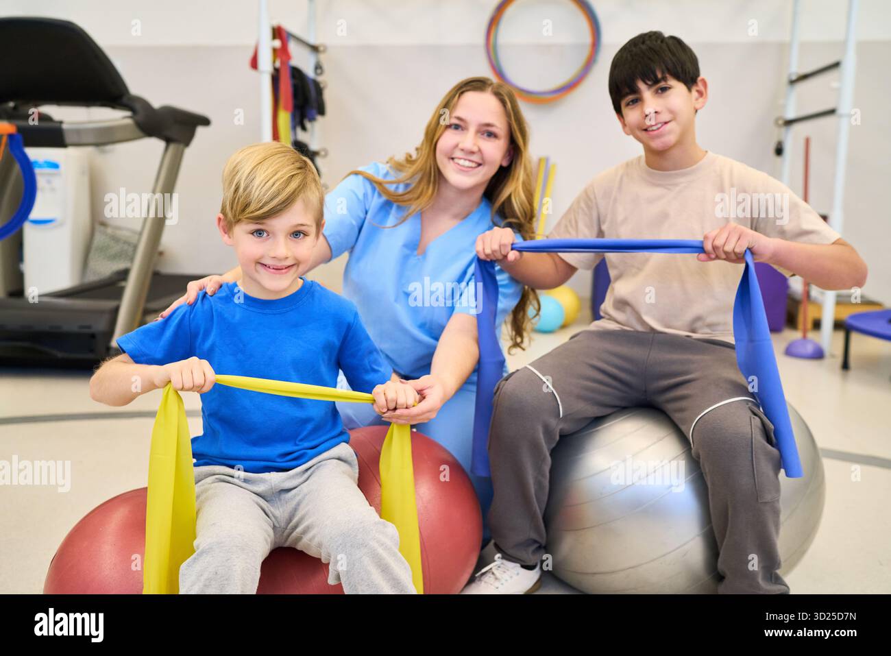A pediatric physiotherapy session where a therapist helps two children ...