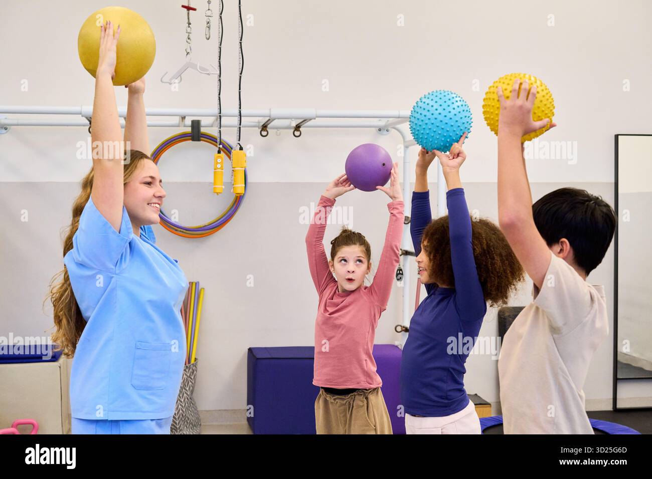 A pediatric physiotherapy session where a therapist guides several kids ...
