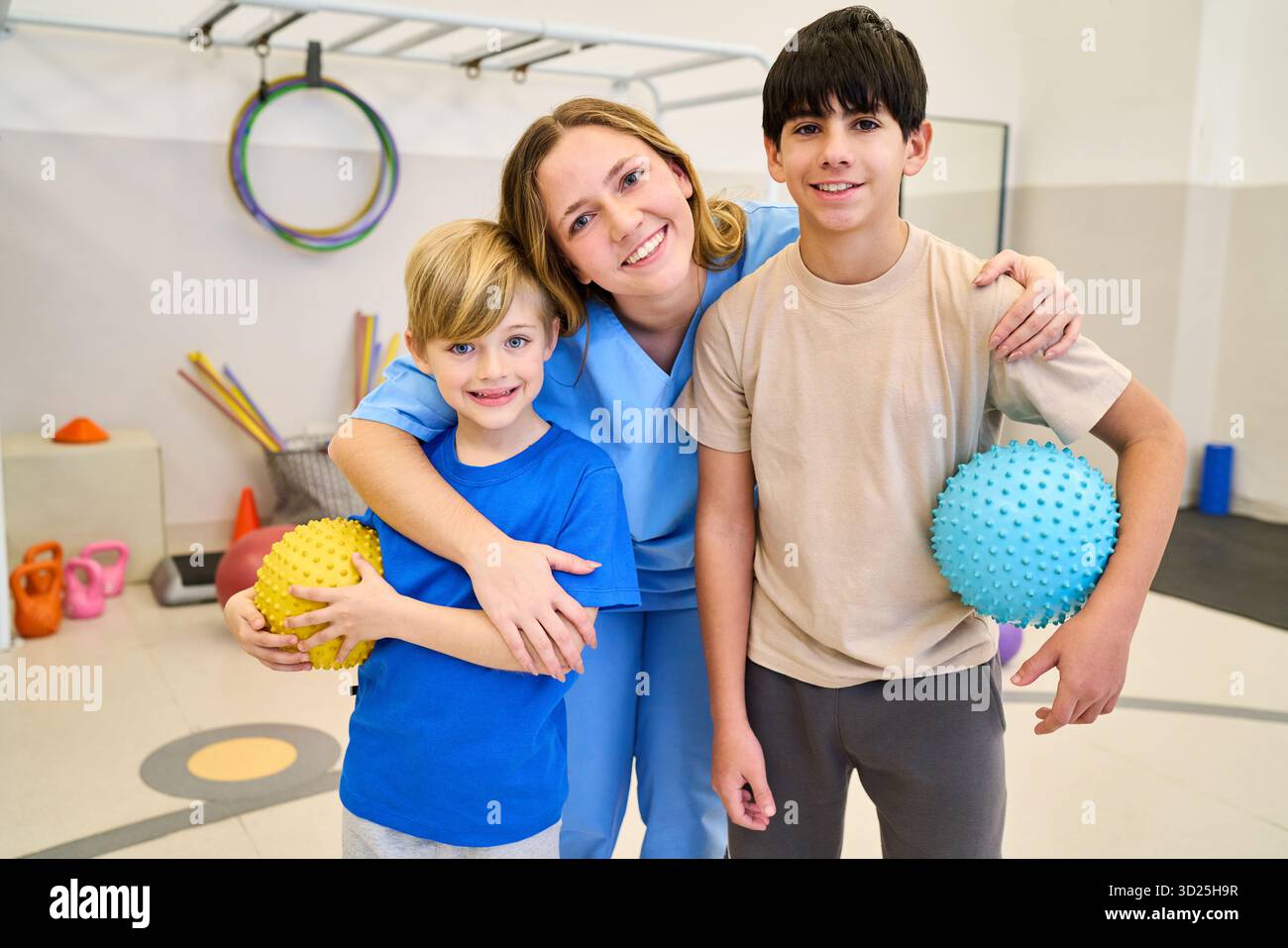 A friendly pediatric physiotherapy session where a therapist guides two ...