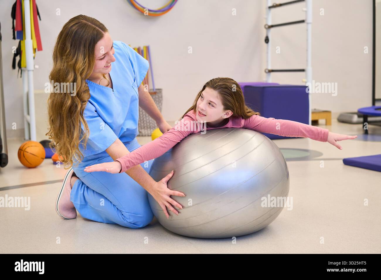 A pediatric physiotherapist guides a young girl through balance and ...