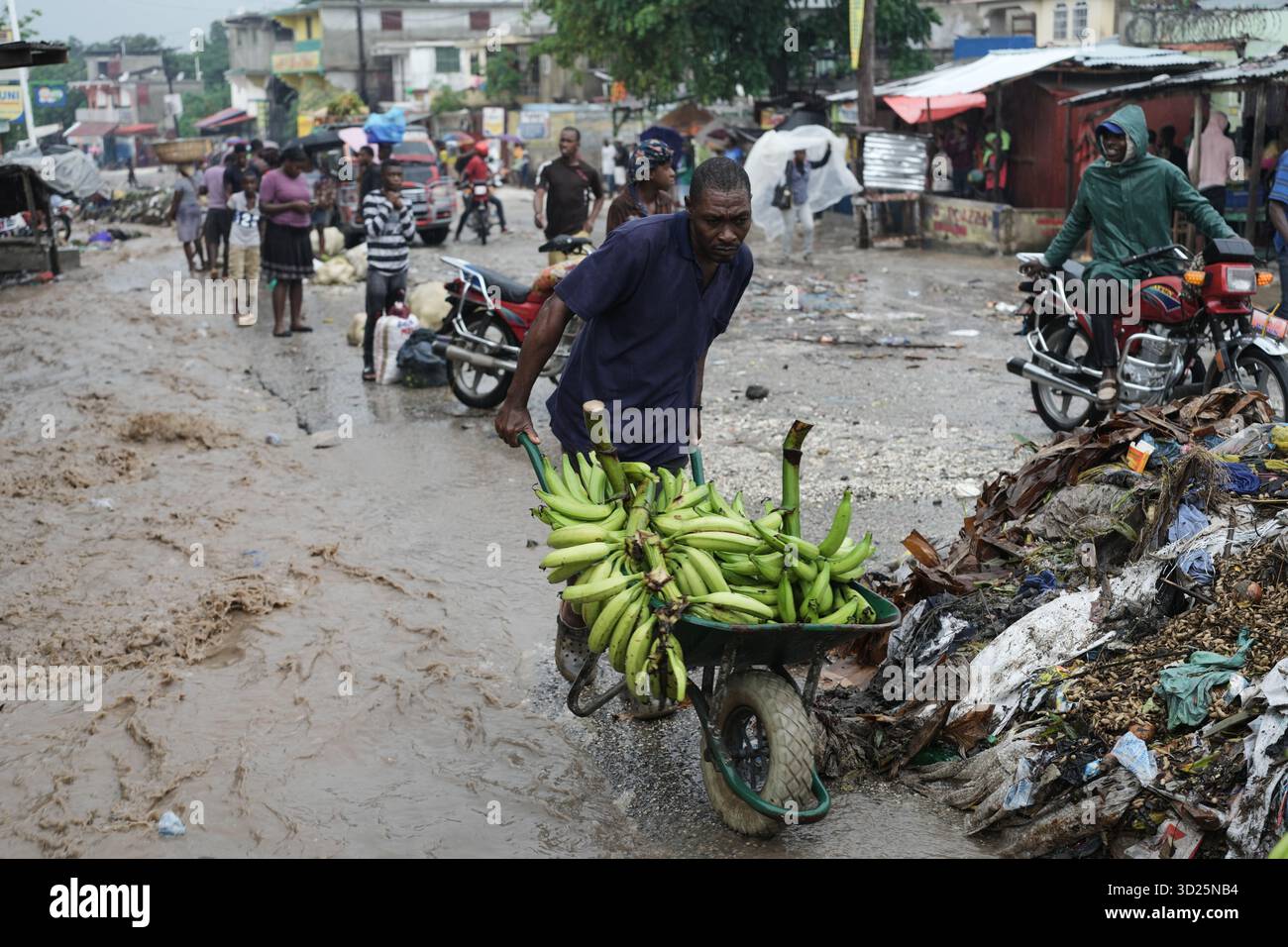 A an pushes a wheelbarrow through a flooded street in the aftermath of ...