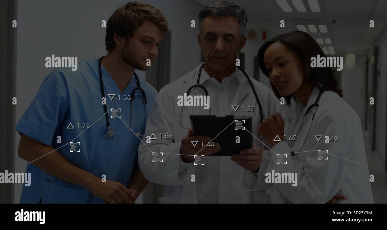 Medical team reviewing digital tablet in hospital corridor, wearing lab ...
