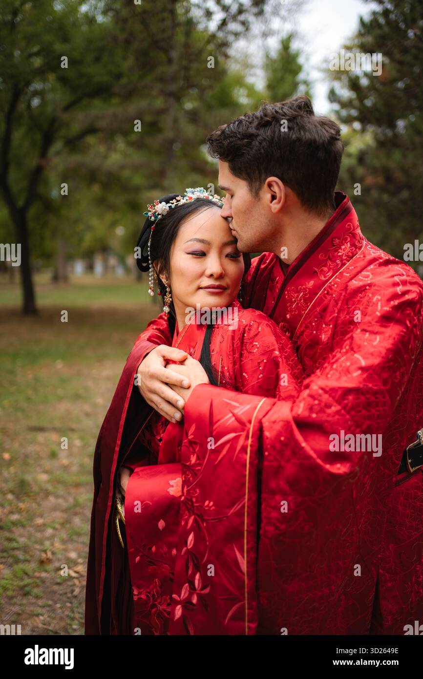 Loving couple in traditional Chinese wedding attire embracing ...