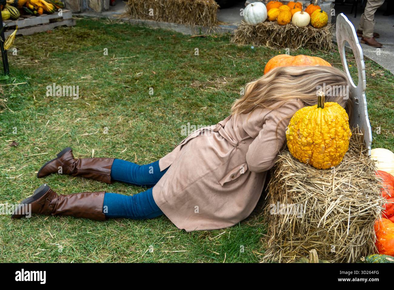 young woman sitting by pumpkin display outdoors, blonde woman in fall ...
