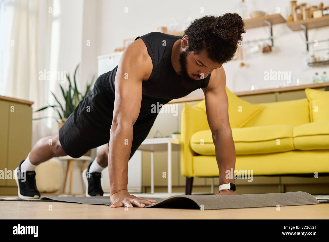 An athletic man works hard on his push-ups at home, showing commitment ...