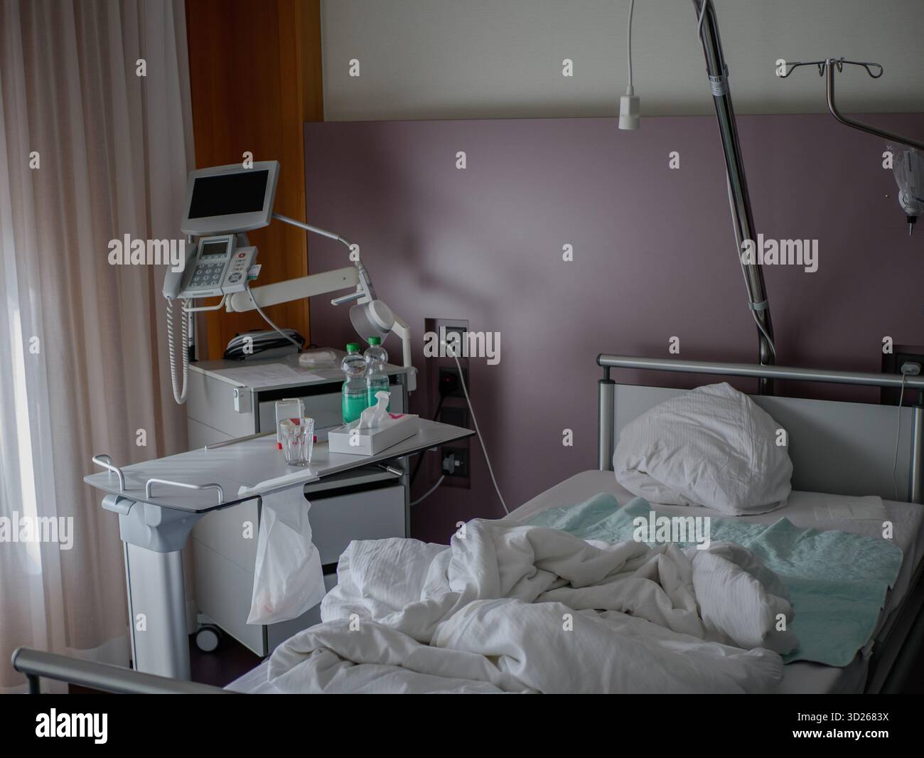 Hospital room with unmade bed, diagnostic monitor, and patient table ...