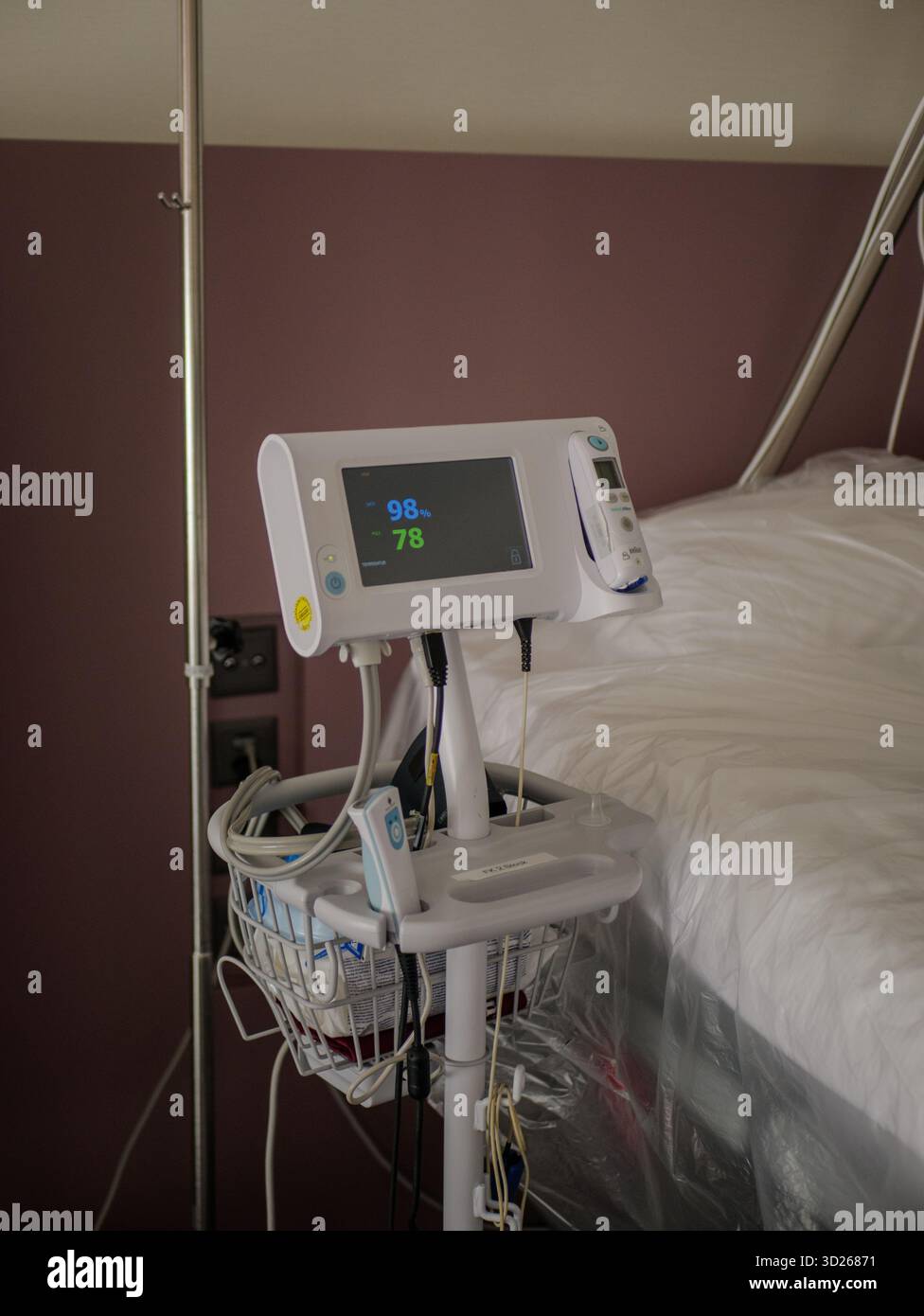 Hospital patient monitor on stand beside bed in recovery room, showing ...
