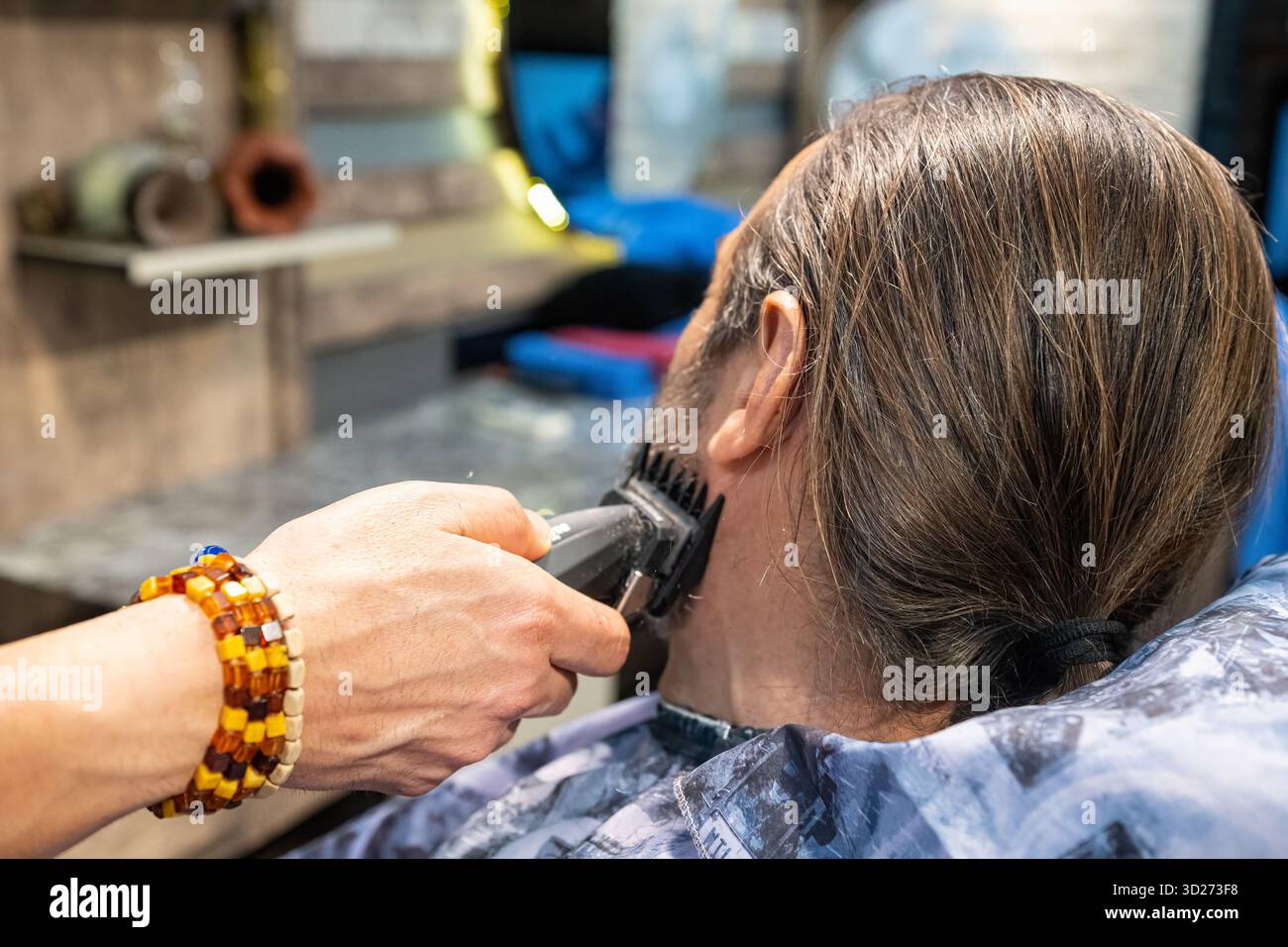 The barber trims the beard and neck area with an electric razor. The ...