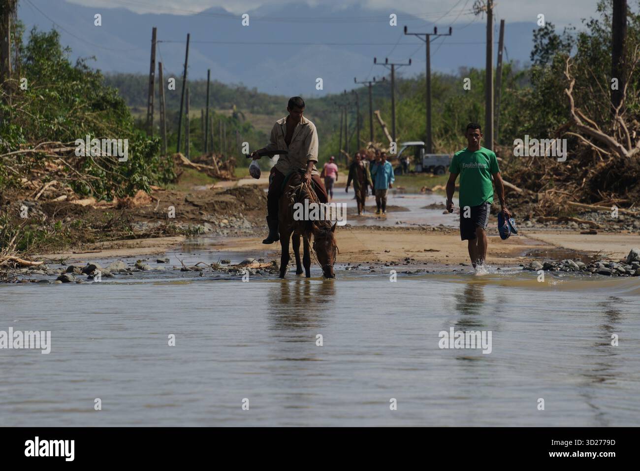 People cross the Sevilla River in Chivirico, Cuba, after Hurricane ...