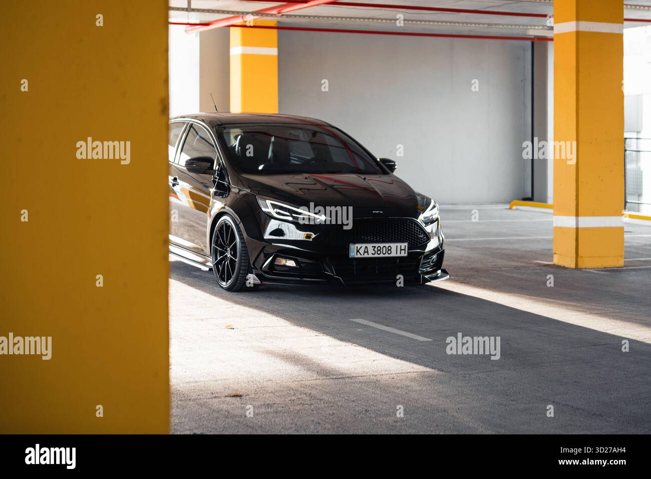 black Ford Focus in parking garage with yellow pillars. Front part of ...