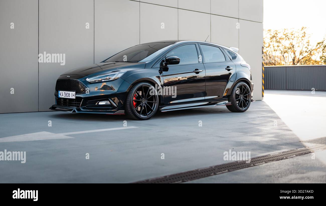 black Ford Focus in front of beige building wall. Three quarter front ...