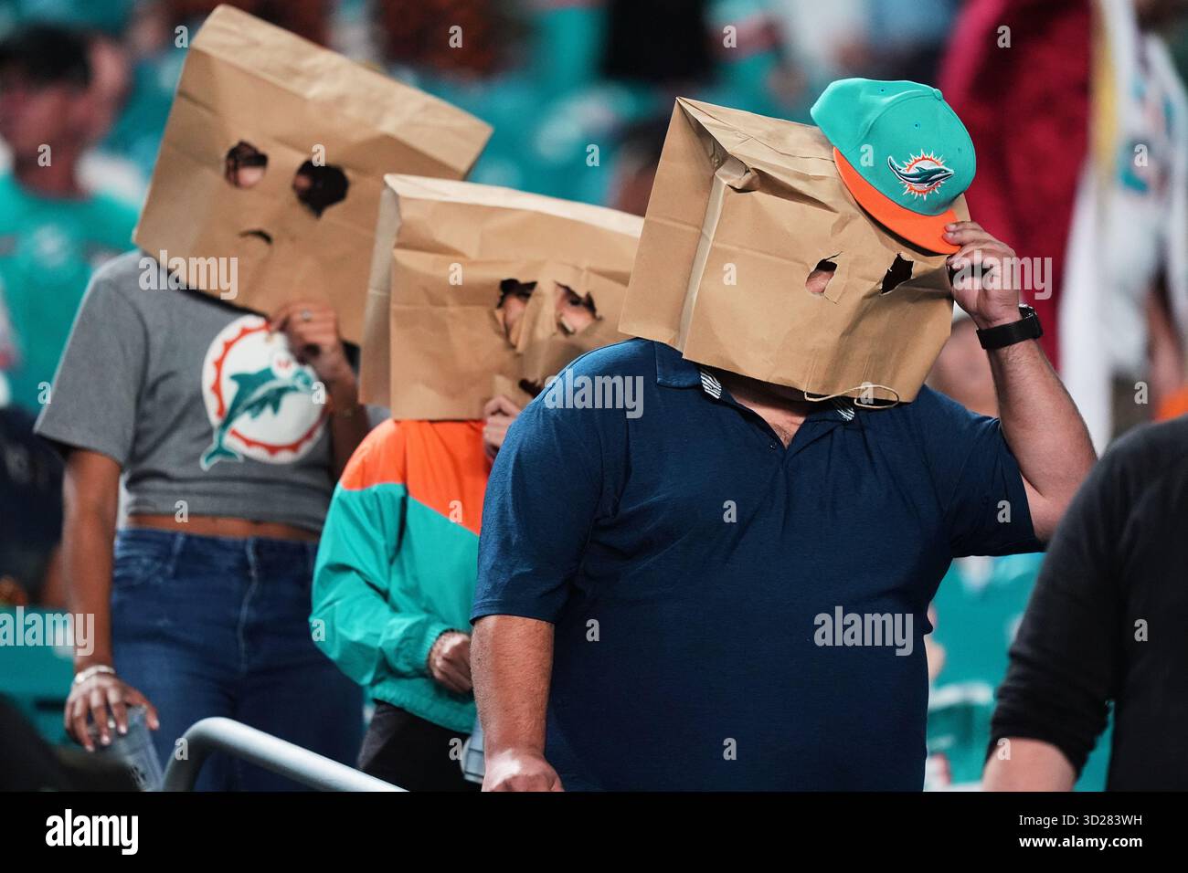 Miami Dolphins fans wear paper bags over their heads as they leave the ...