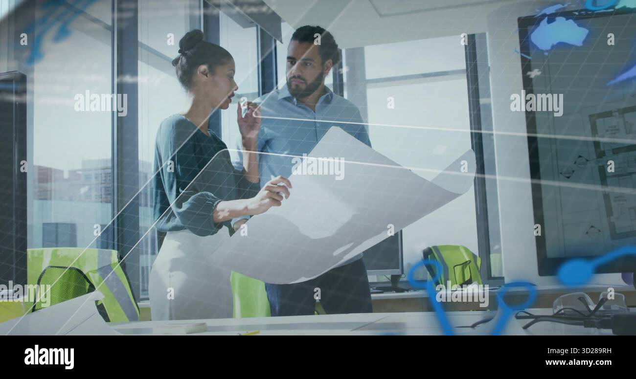 Two colleagues wearing business attire studying blueprint at office ...
