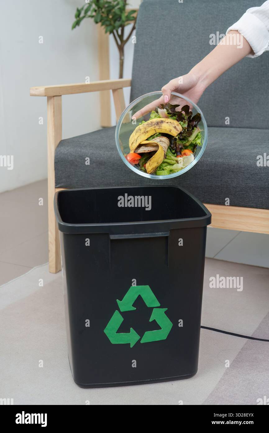 Sustainability. Woman disposing of food waste in a recycling bin Stock ...