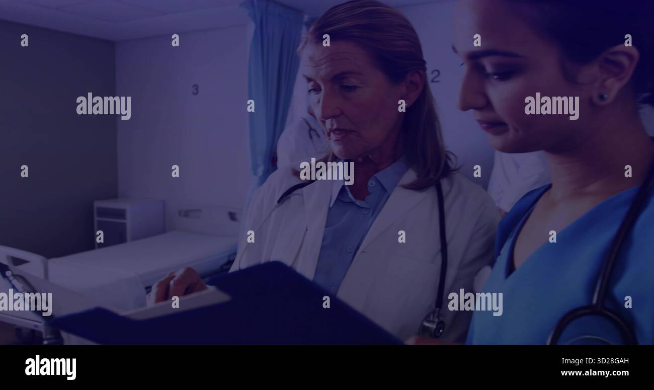 Standing doctor and nurse reading chart in hospital room, with ...